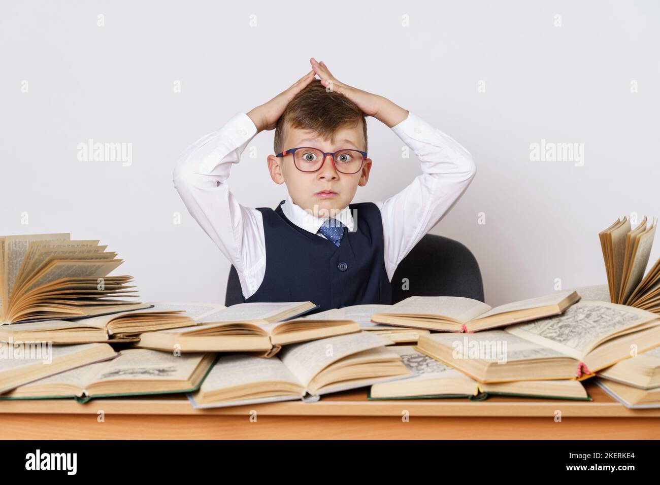 The student does his homework, holds his head with his hands and looks ...