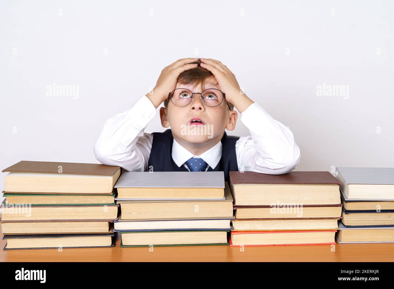 Education concept. The student sits at the table and holds his head ...