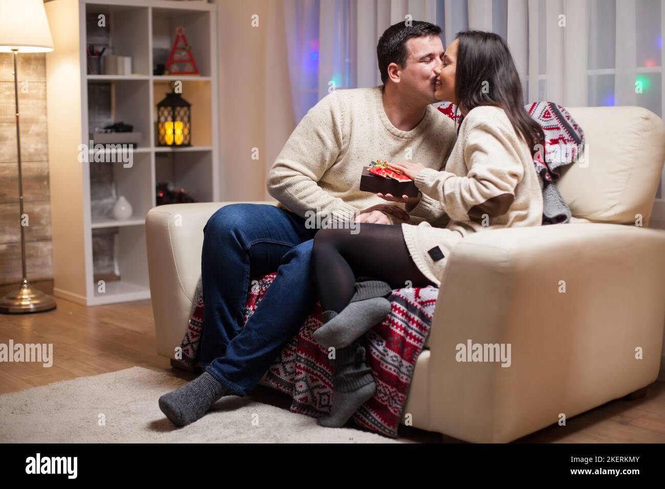 Young man kissing his wife cheek on christmas day after receiving a ...
