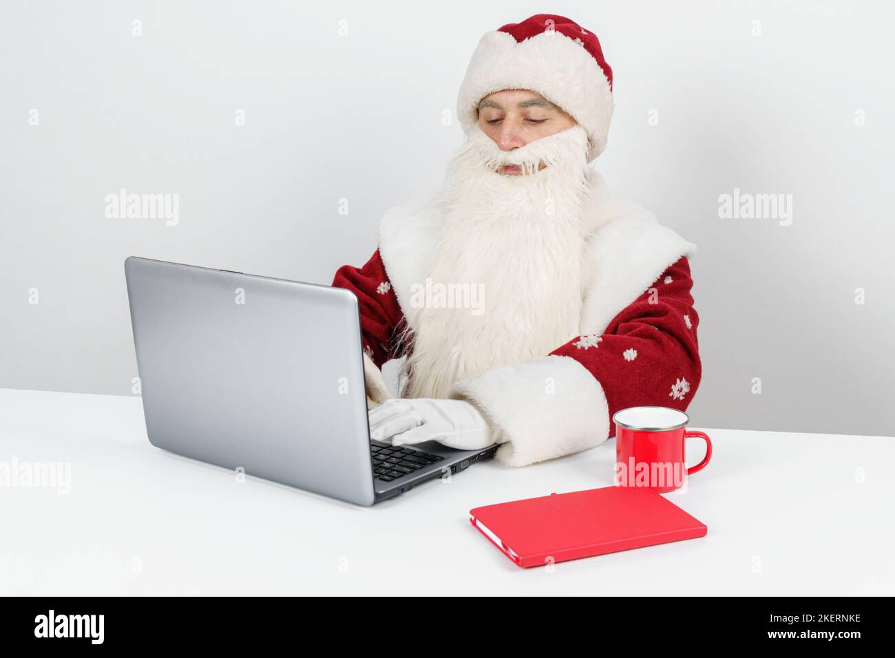 Christmas and New Year concept. Santa Claus sits at his desk and works ...