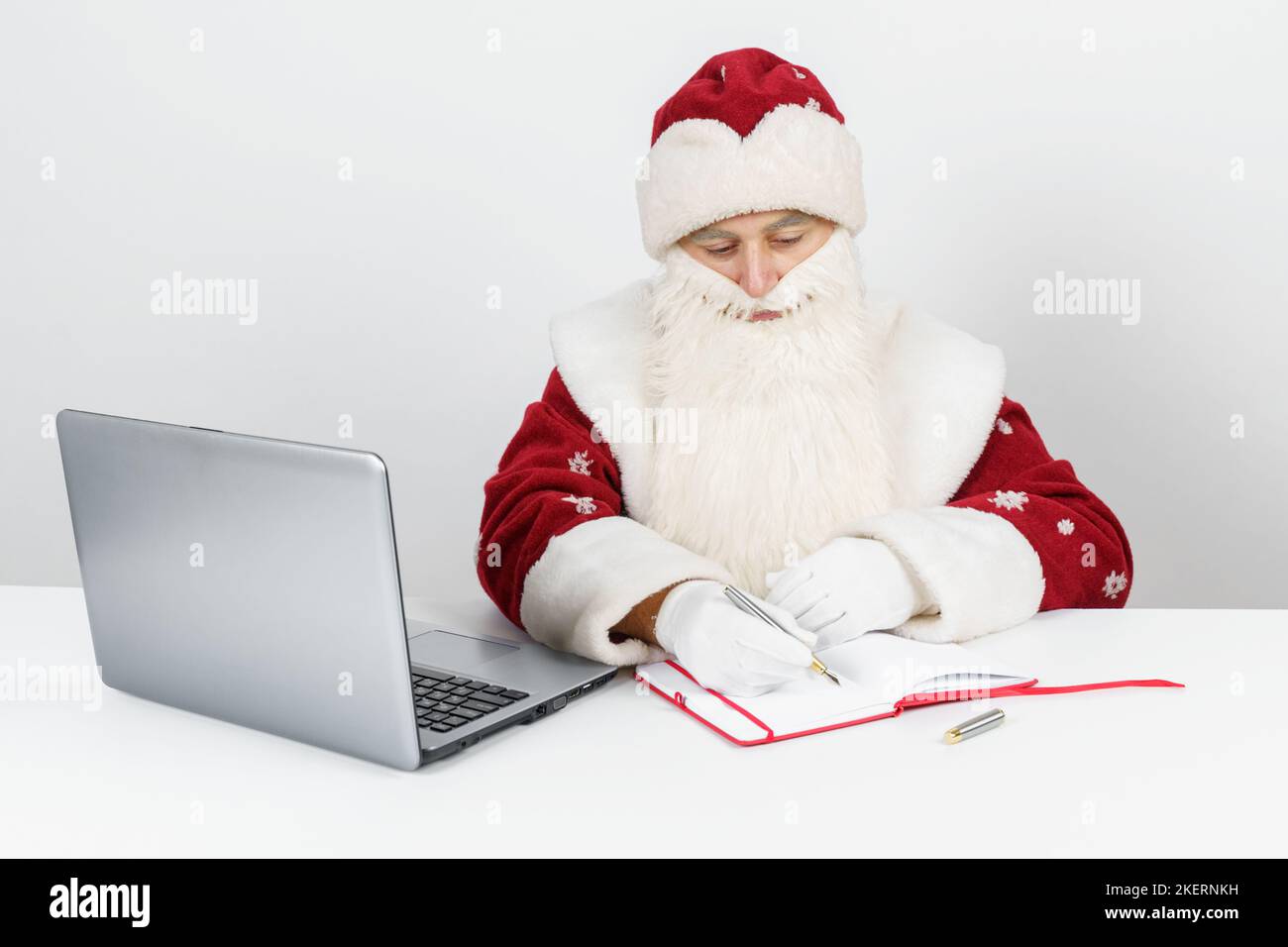 Christmas and New Year concept. Santa Claus sits at his desk and writes ...