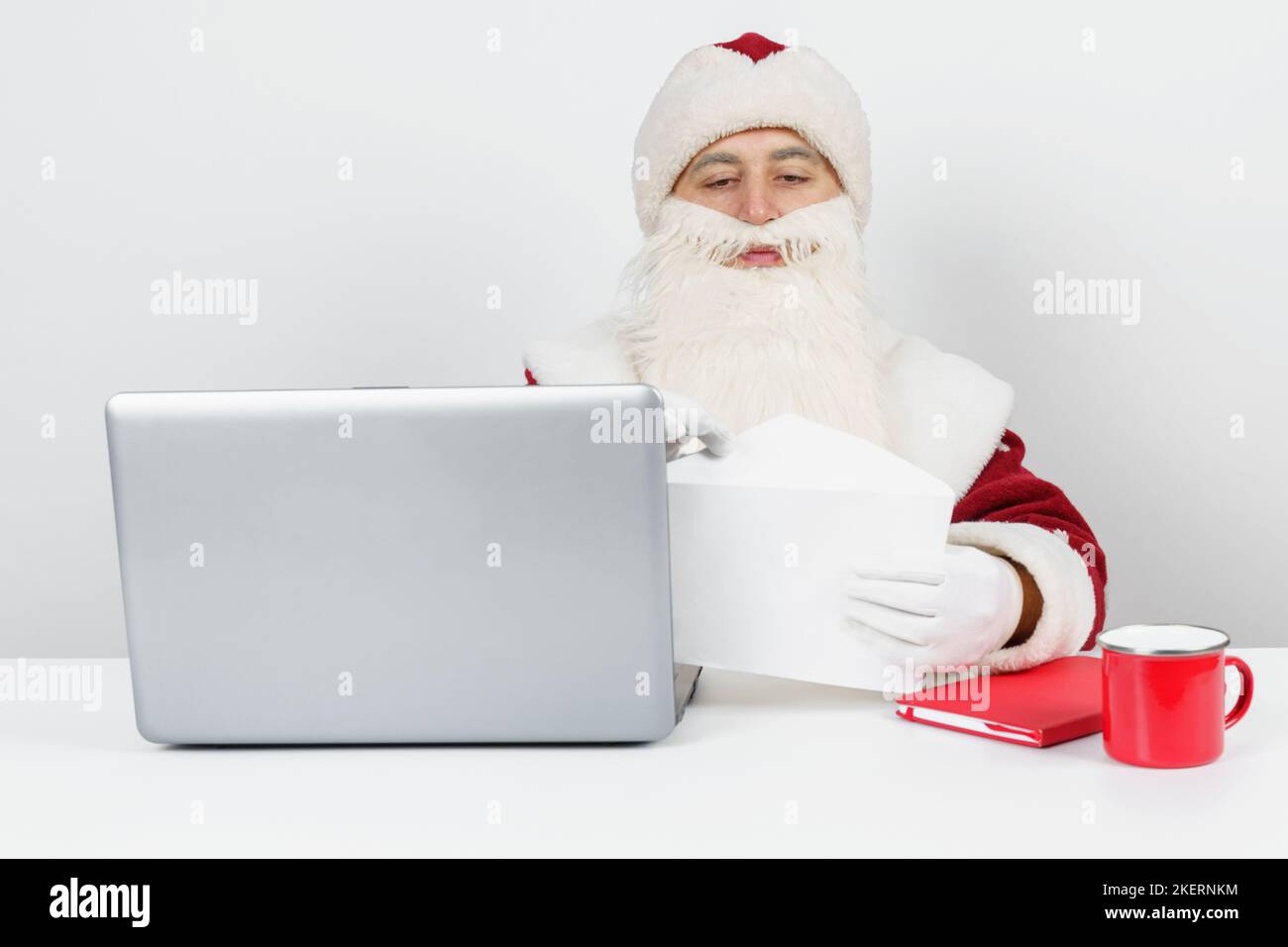 Christmas and New Year concept. Santa Claus is sitting at his desk and ...