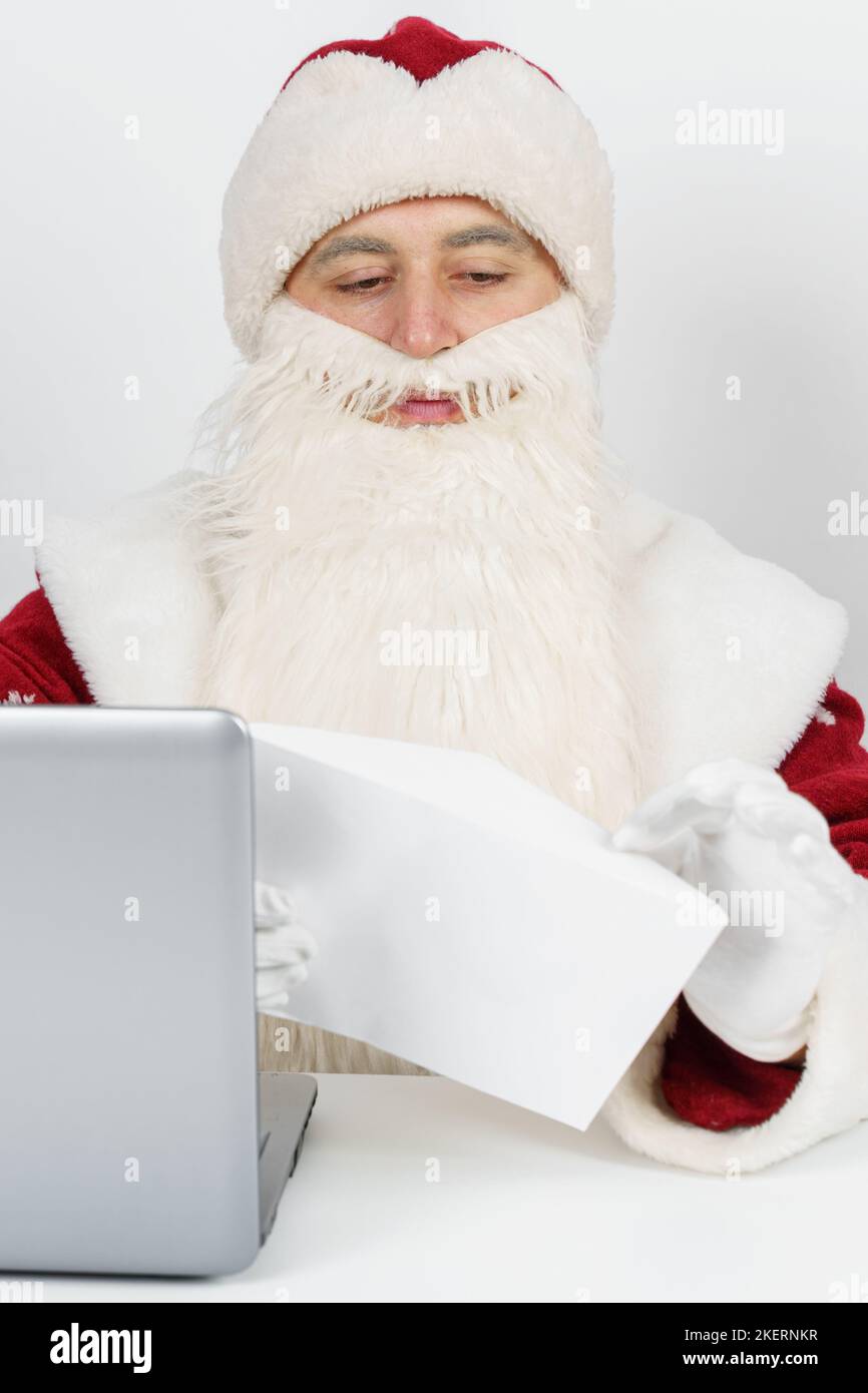 Christmas and New Year concept. Santa Claus is sitting at his desk and ...
