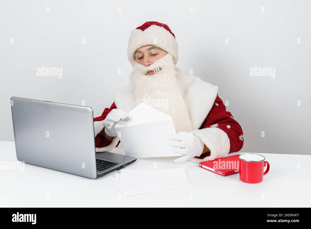 Christmas and New Year concept. Santa Claus is sitting at his desk and ...