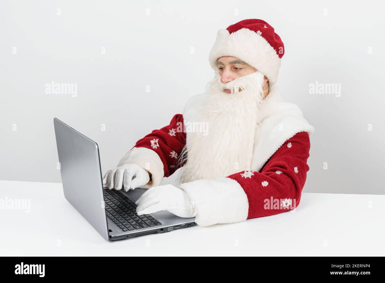 Christmas and New Year concept. Santa Claus sits at his desk and works ...
