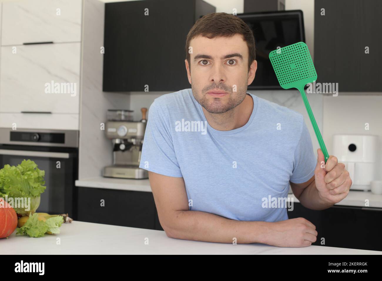 Man trying to catch a fly in his kitchen Stock Photo - Alamy