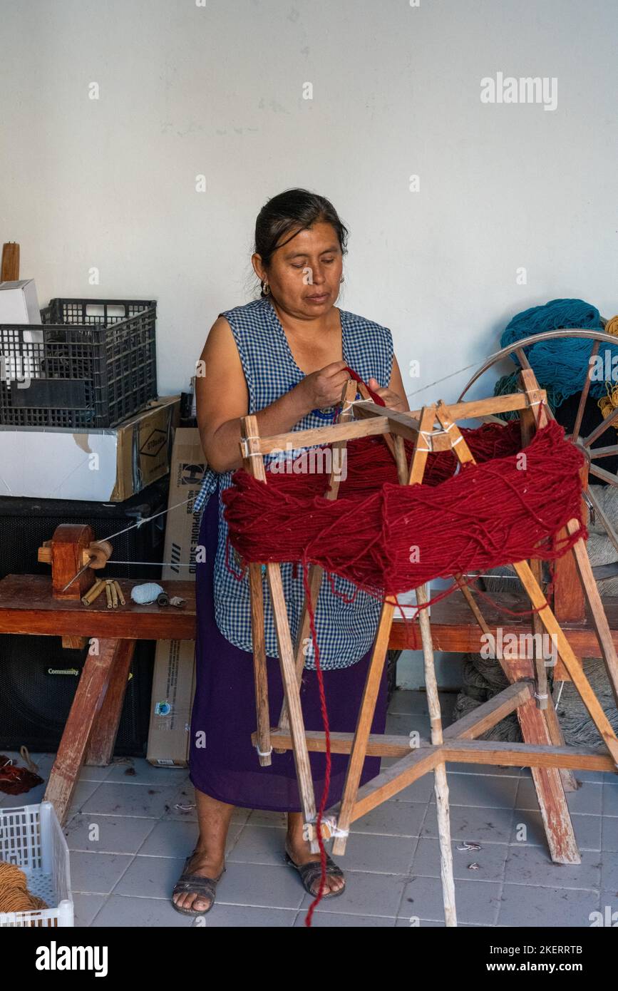 A woman winding yarn for making woolen rugs in the weaving center of ...