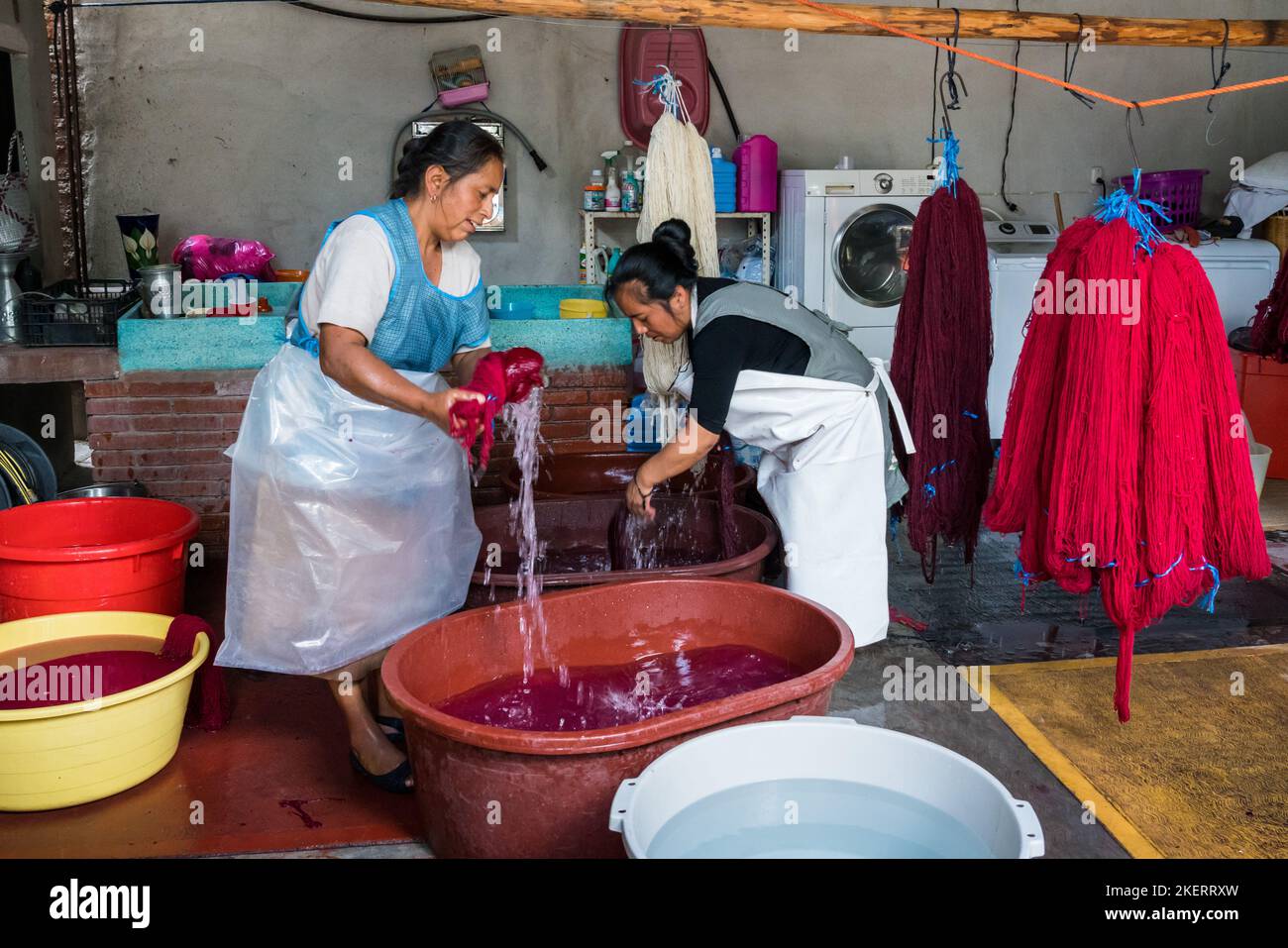 Women in a weaving workshop wash skeins of yarn after dying with ...
