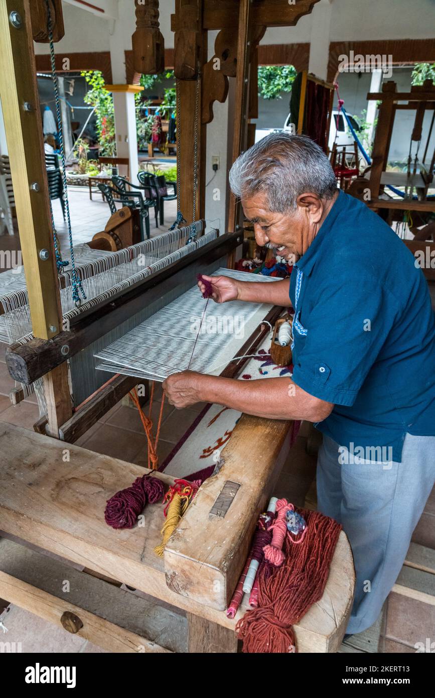 A master weaver weaves a woolen rug on a wooden foot treadle loom in ...
