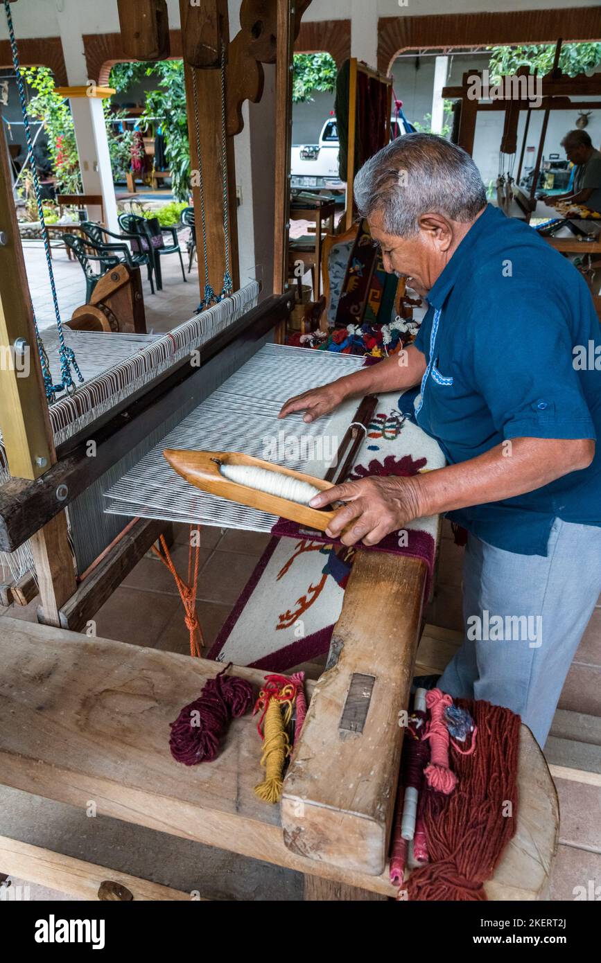 A master weaver weaves a woolen rug on a wooden foot treadle loom in ...