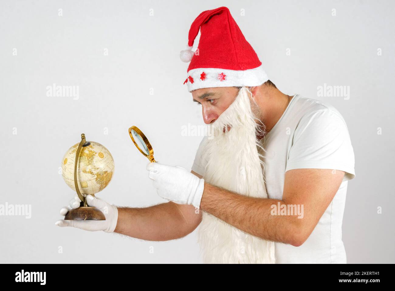 Christmas and New Years concept. Santa Claus is studying the globe with ...