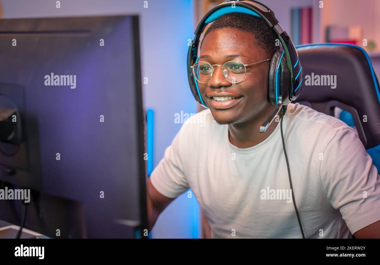 African American man playing action video games on computer stream ...