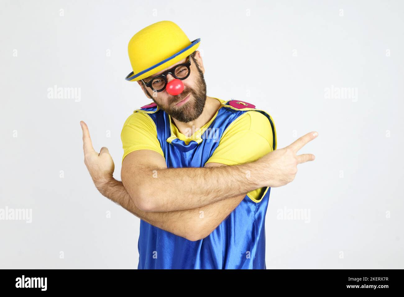 Holiday concept. A clown in a bright blue and yellow suit hugs himself ...