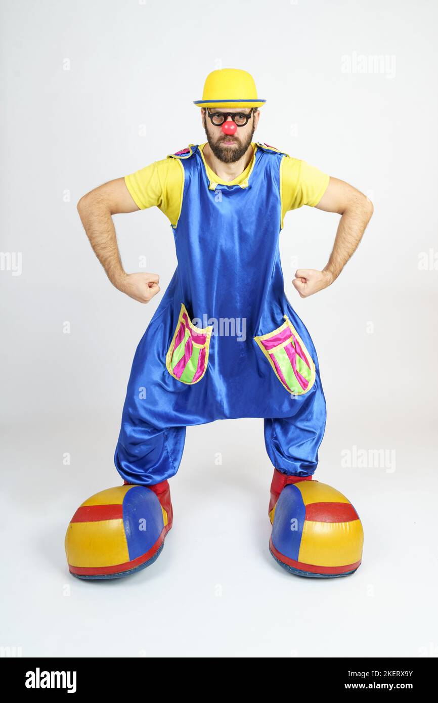 Holiday concept. A clown in a bright blue and yellow suit shows off his ...
