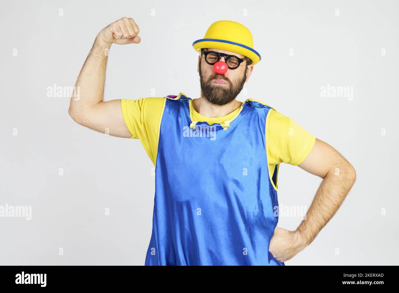 Holiday concept. A clown in a bright blue and yellow suit shows off his ...