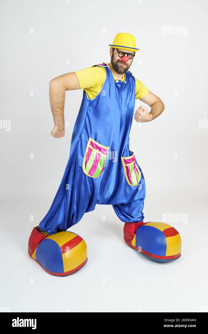 Holiday concept. A clown in a bright blue and yellow suit shows off his ...