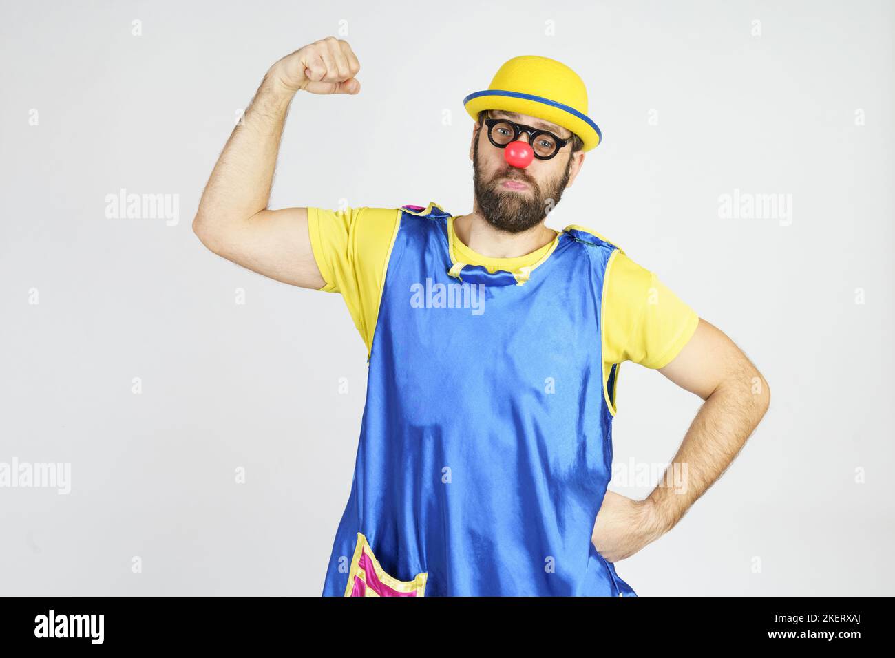 Holiday concept. A clown in a bright blue and yellow suit shows off his ...