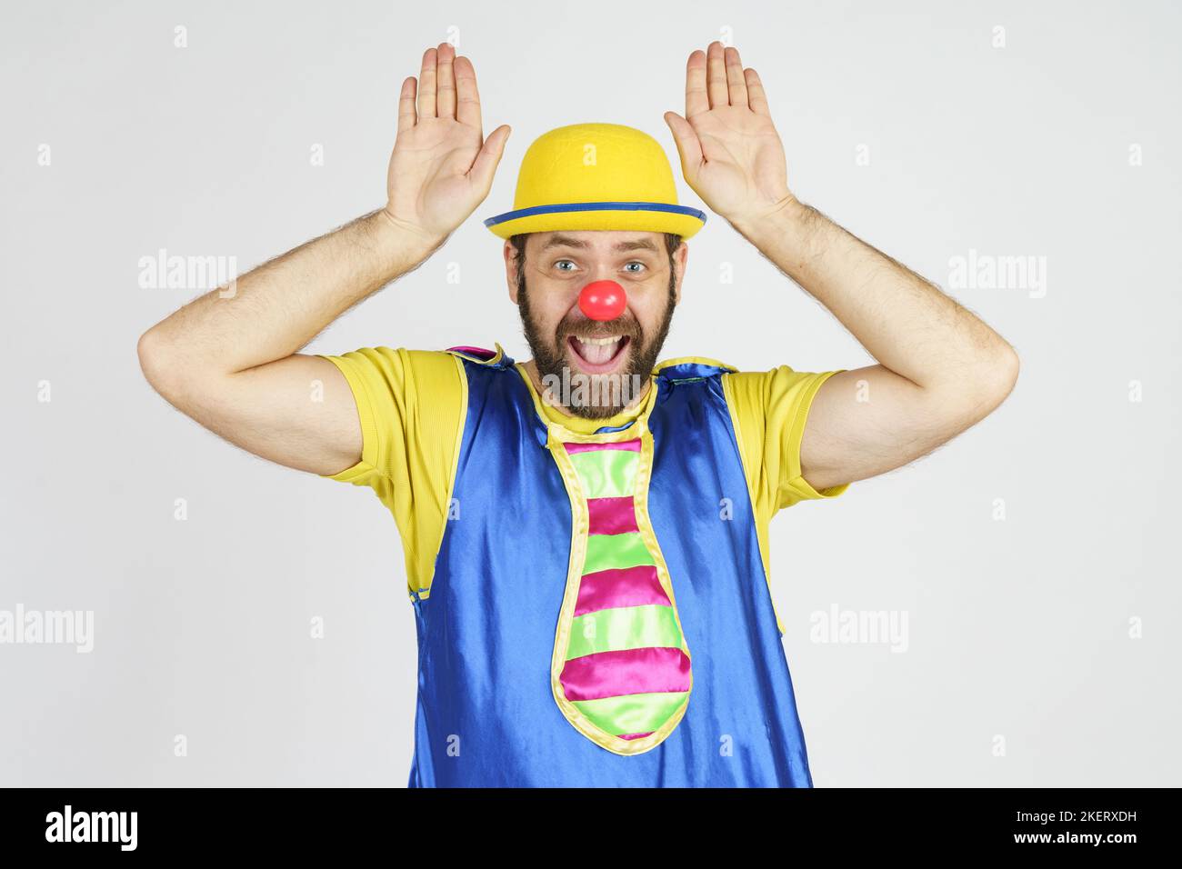 Holiday concept. Clown in a bright blue and yellow suit shows hand ...