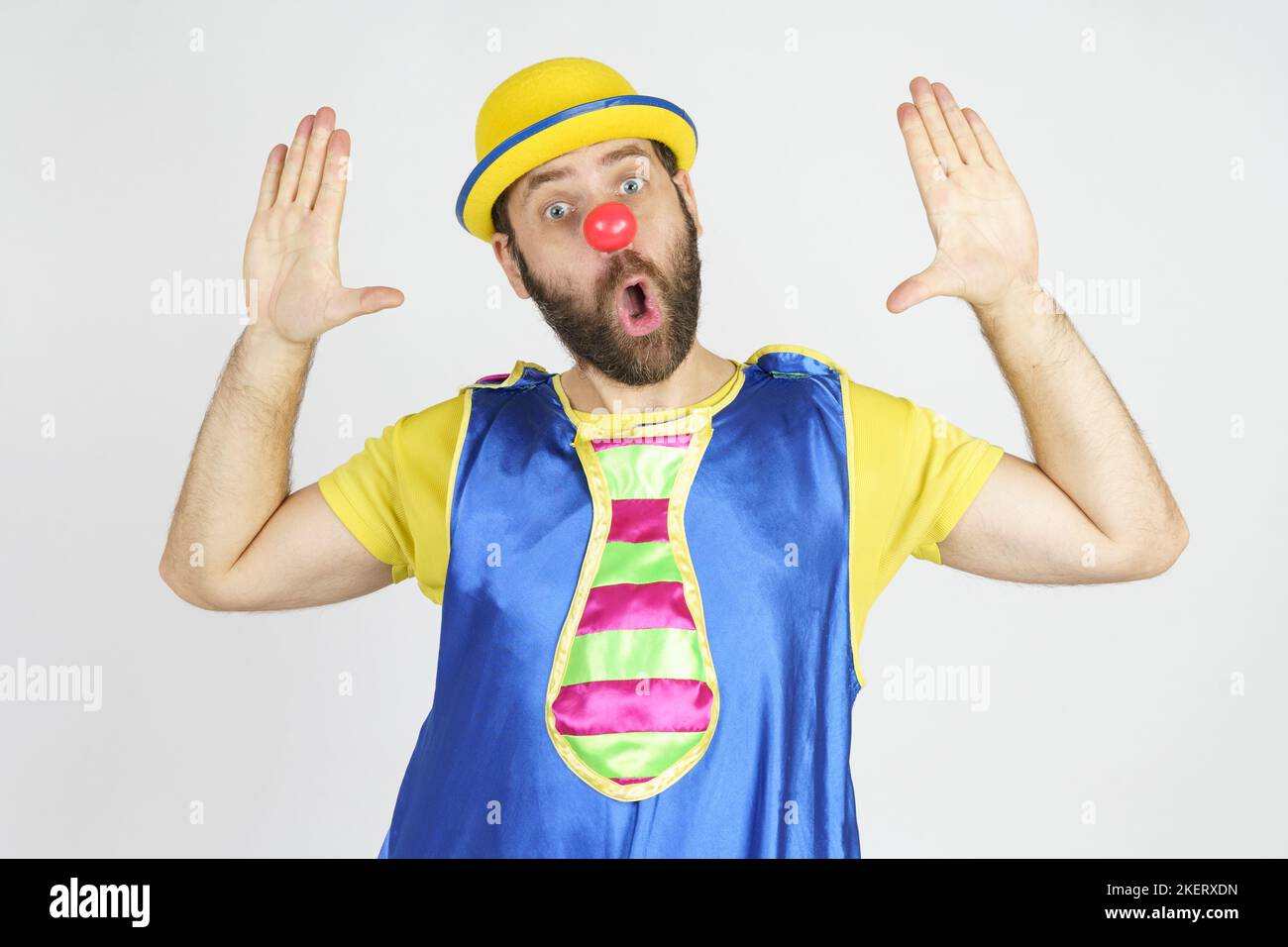 Holiday concept. Clown in a bright blue and yellow suit shows hand ...