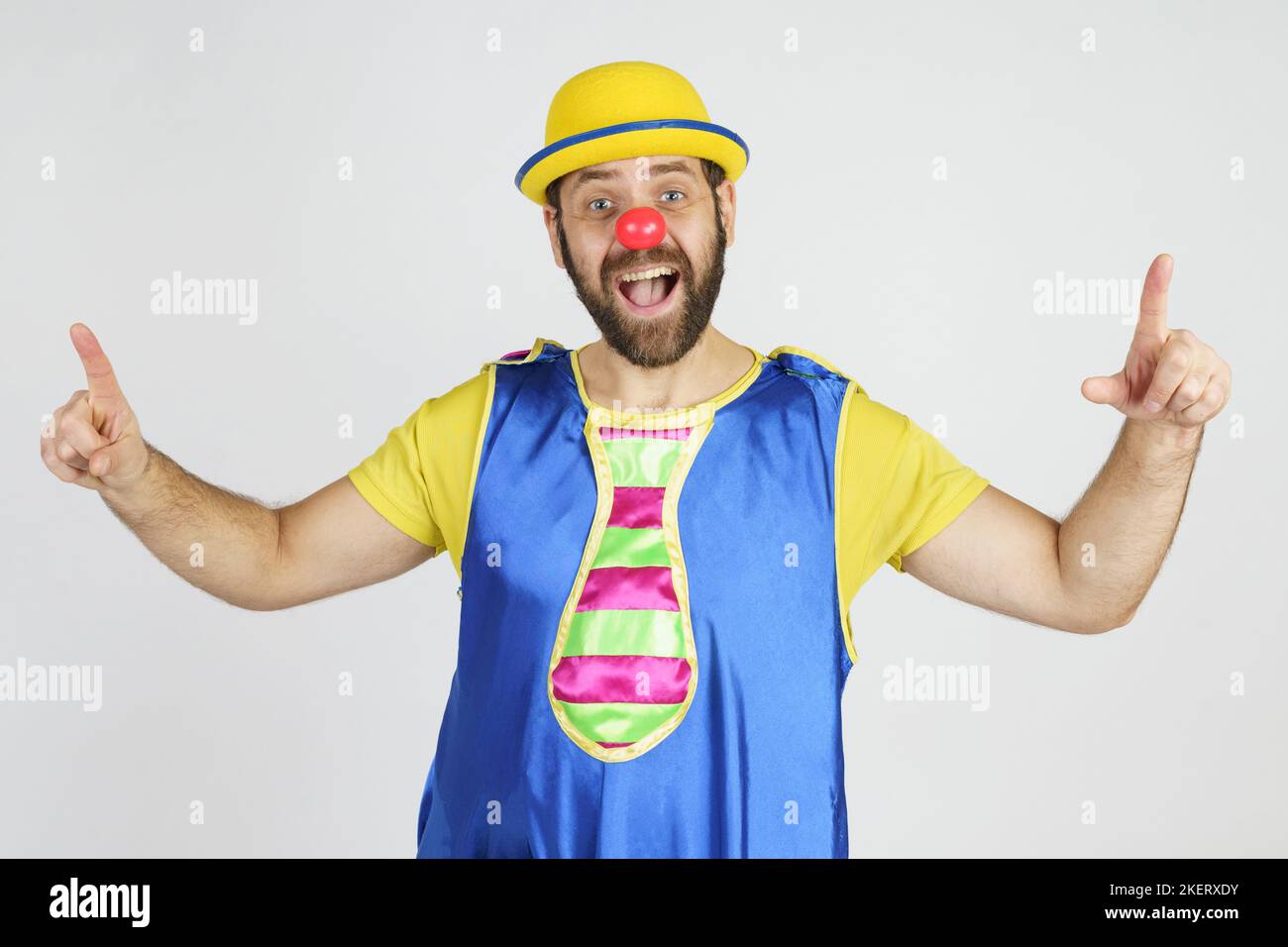 Holiday concept. Clown in a bright blue and yellow suit points fingers ...