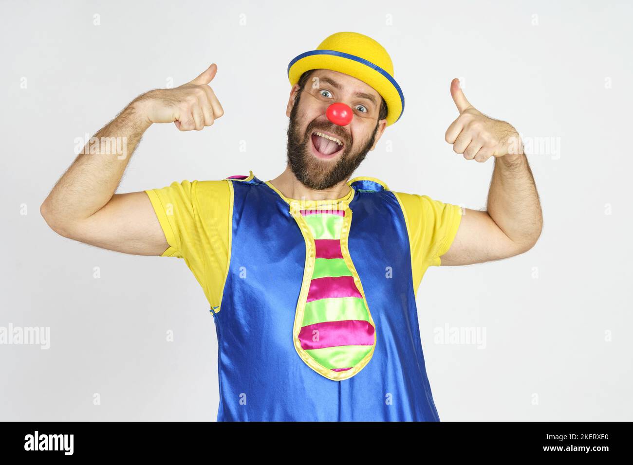 Holiday concept. Clown in a bright blue and yellow suit points fingers ...