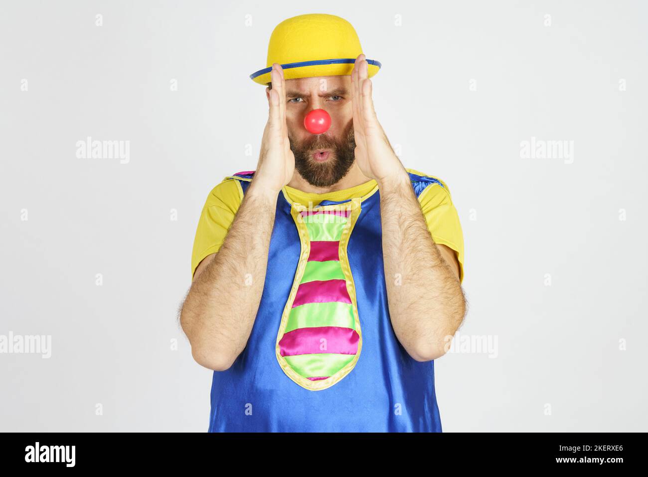 Holiday concept. A clown in a bright blue and yellow suit shows ...