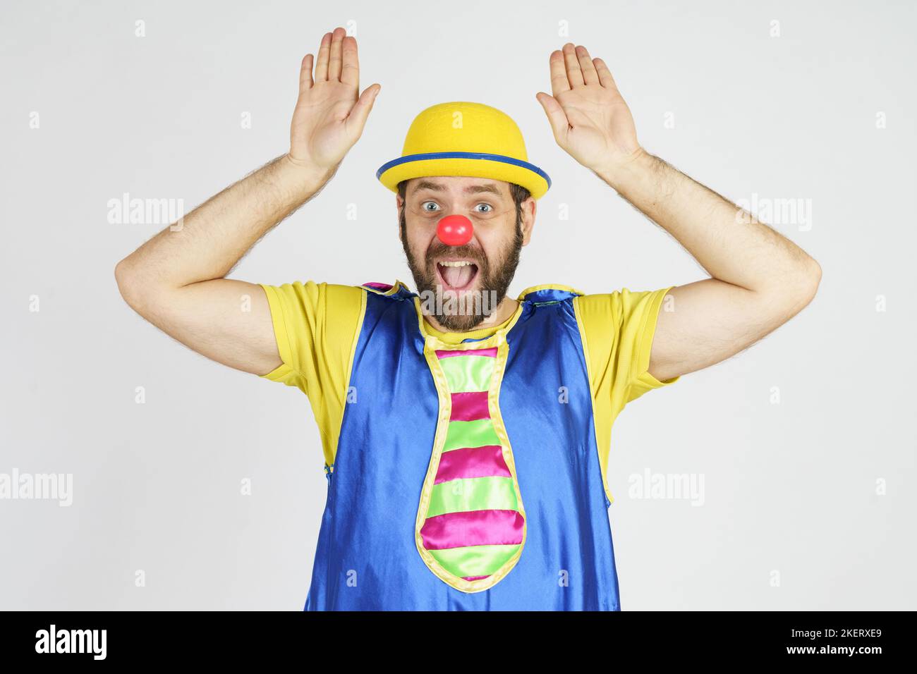 Holiday concept. Clown in a bright blue and yellow suit shows hand ...