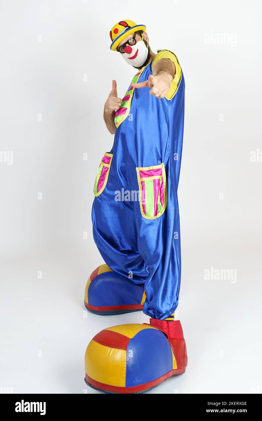Holiday concept. A clown in a bright blue and yellow suit, glasses and ...
