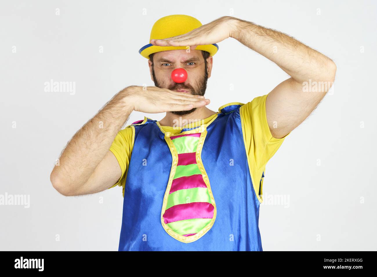 Holiday concept. Clown in a bright blue and yellow suit shows hand ...