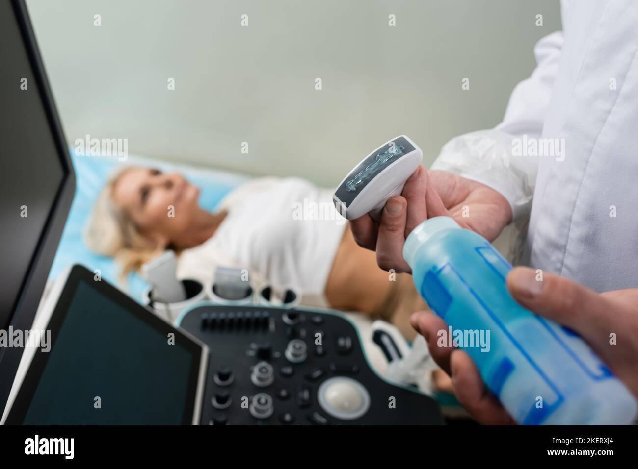 doctor applying ultrasonic gel on ultrasound probe near patient lying ...