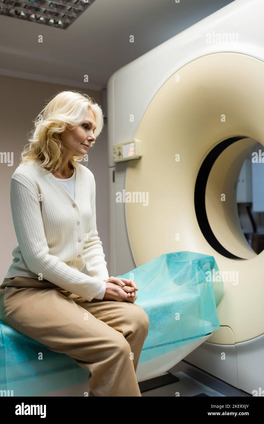 pensive middle aged woman sitting near ct scanner in hospital,stock ...