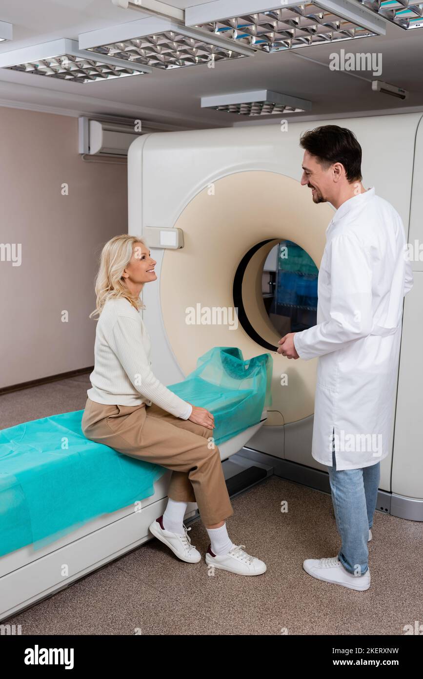 radiologist in white coat talking to smiling mature woman sitting near ...