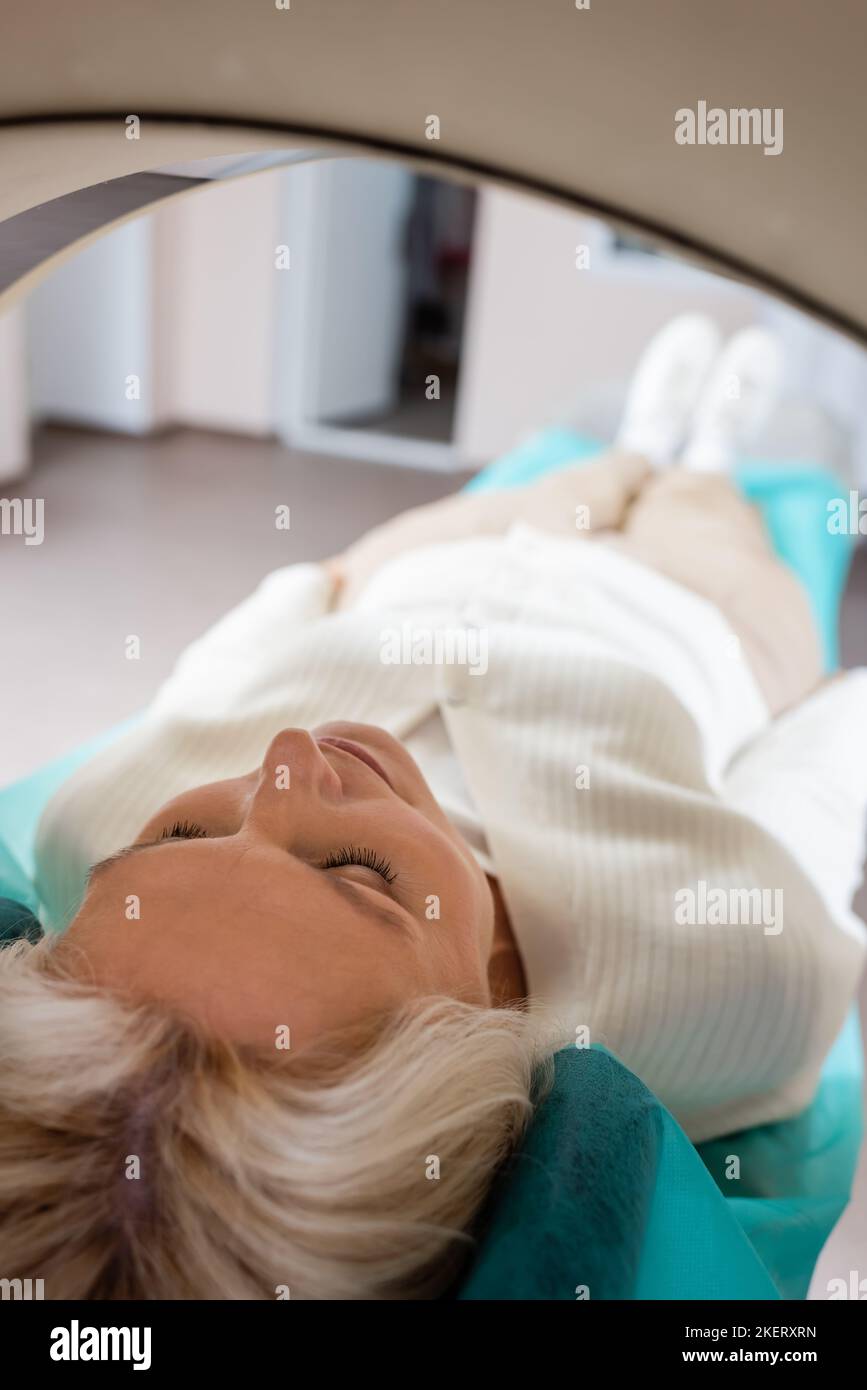 mature woman with closed eyes lying during diagnostics on ct scanner on ...