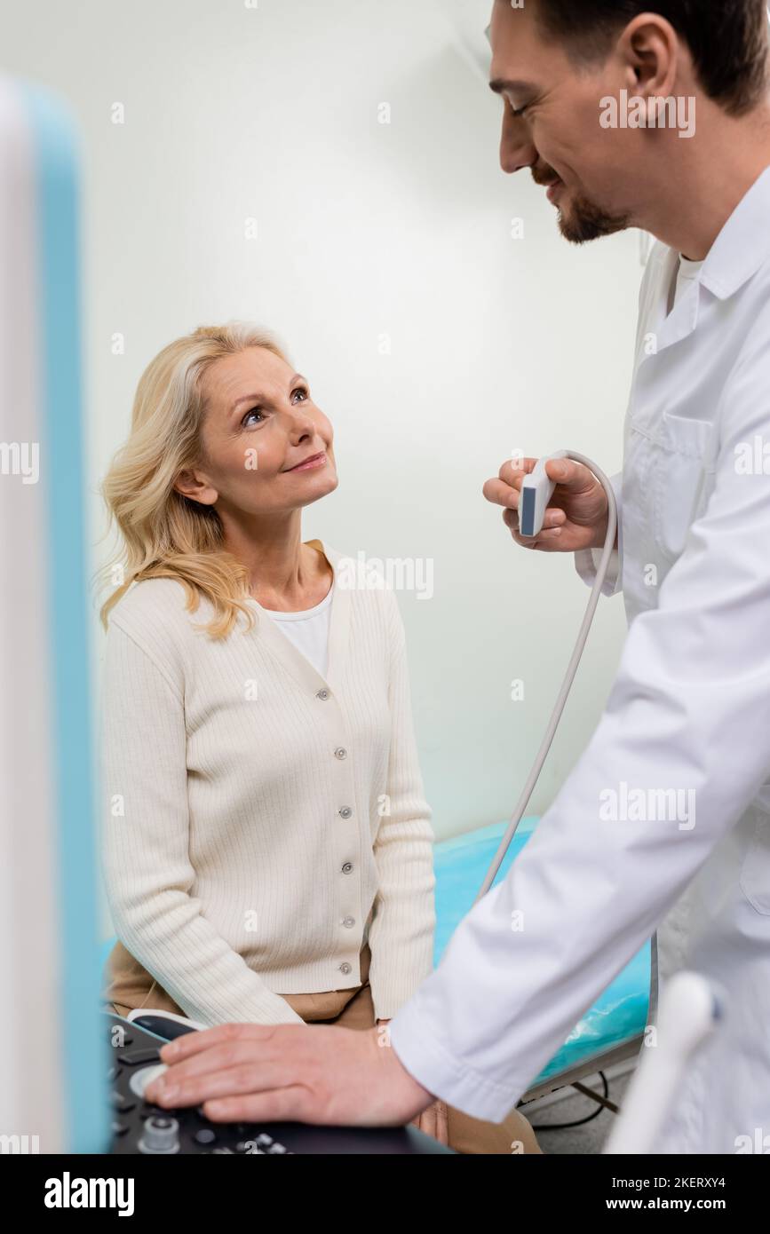 happy doctor with ultrasound probe looking at happy blonde woman in ...