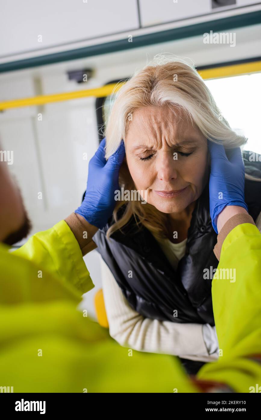Paramedic giving first aid to middle aged woman suffering from pain in ...