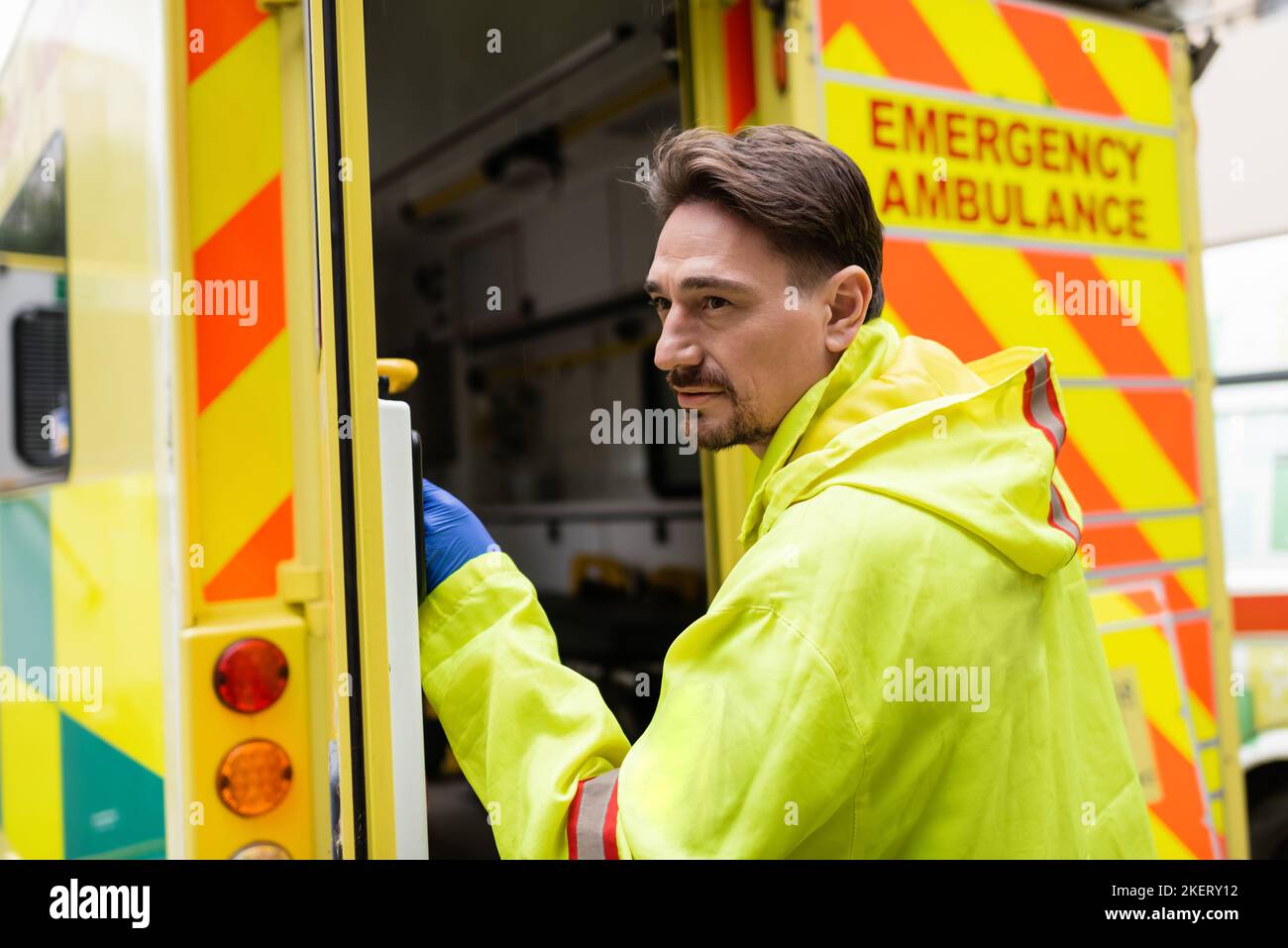 Paramedic standing near blurred ambulance car with open door outdoors ...