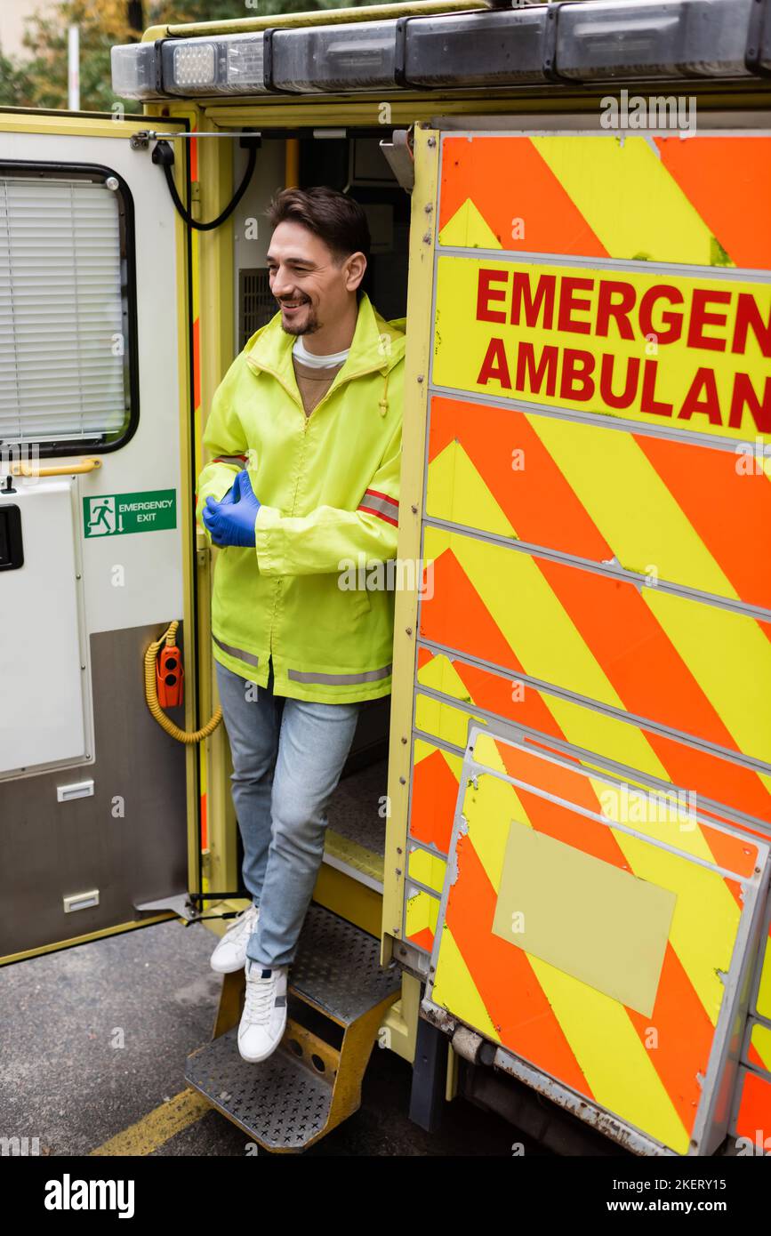 Full length of smiling paramedic standing near ambulance vehicle ...