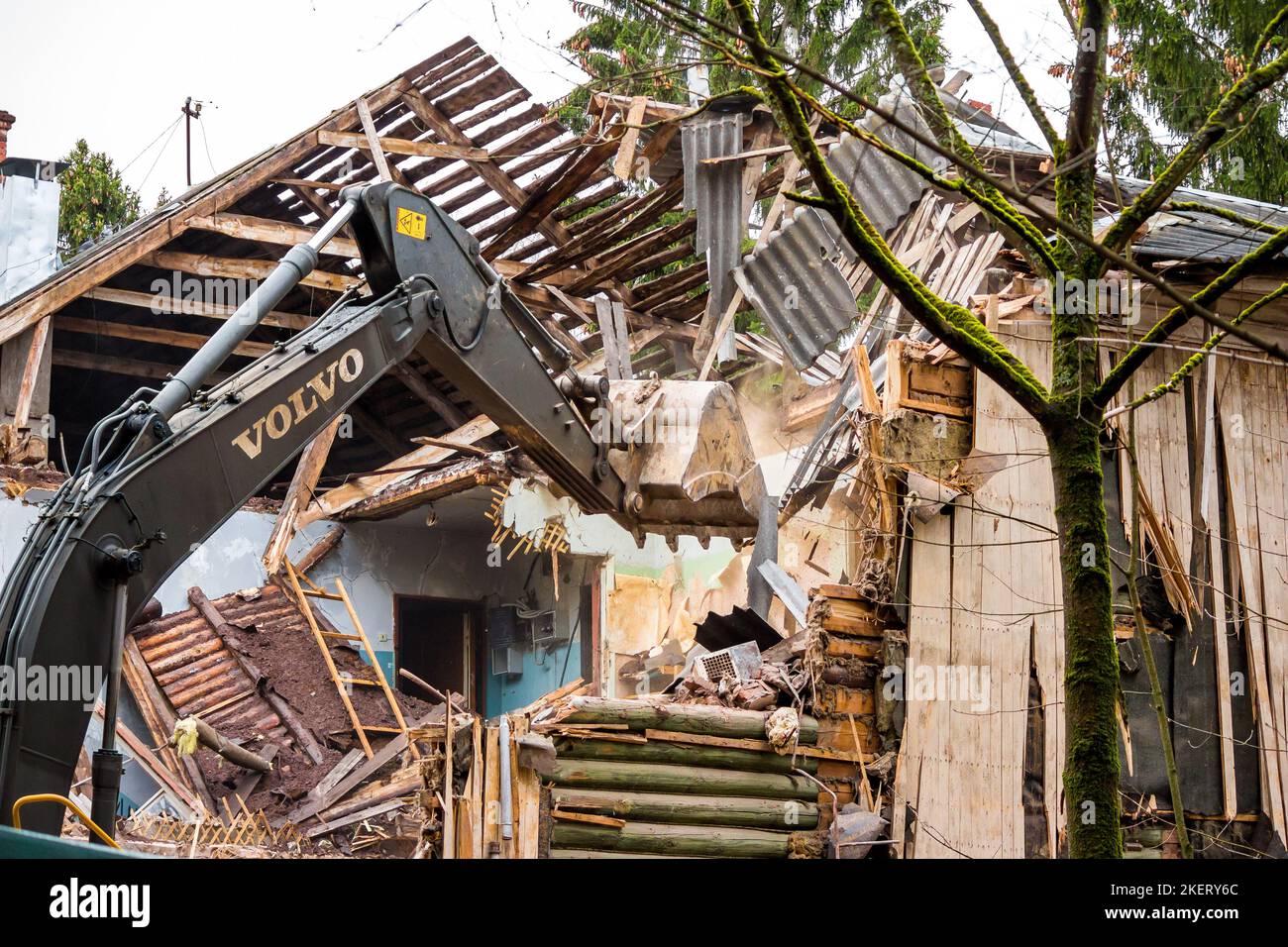 Demolition of an old wooden log house with a Volvo excavator, the ...
