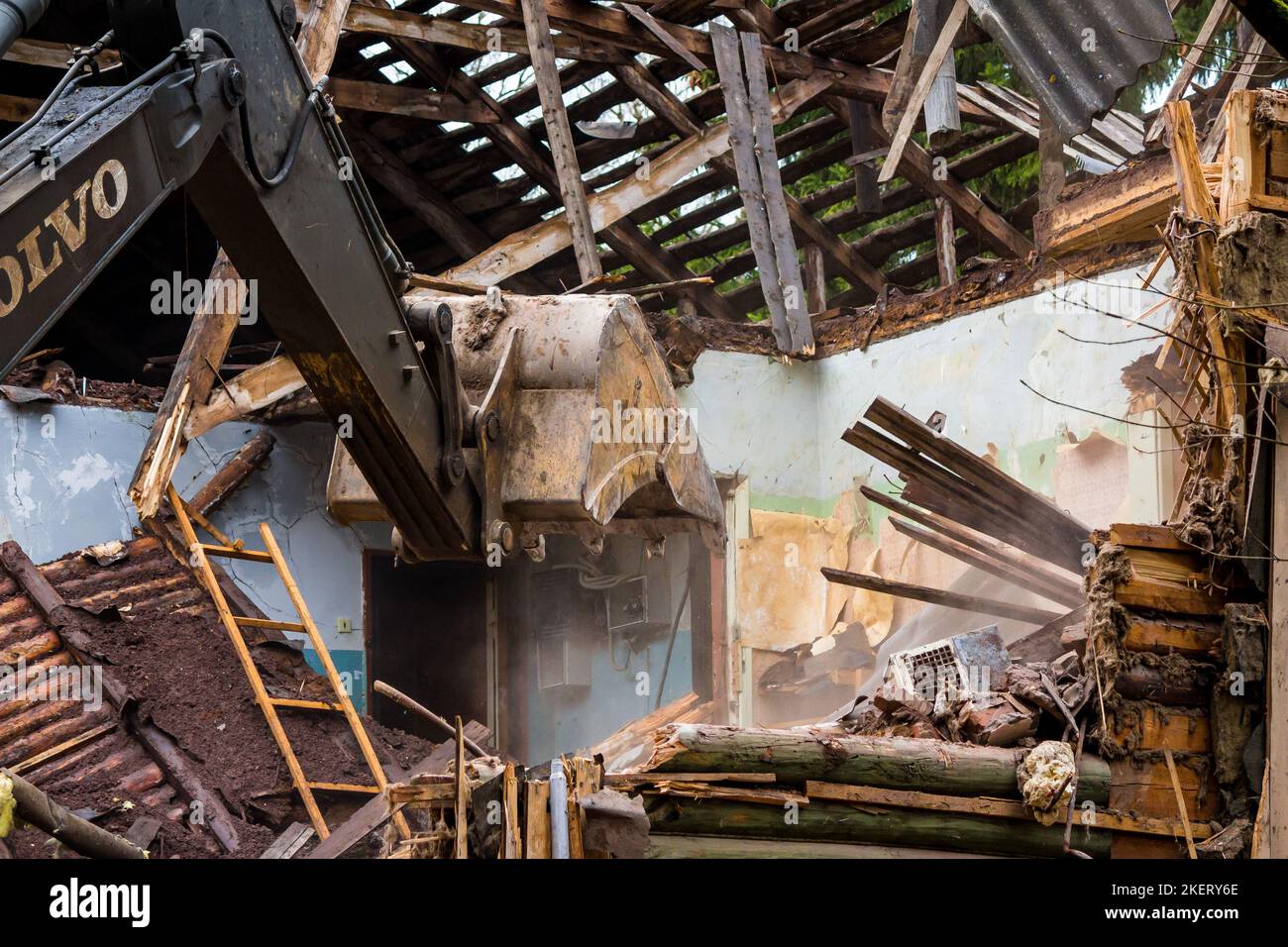 Demolition of an old wooden log house with a Volvo excavator, the ...