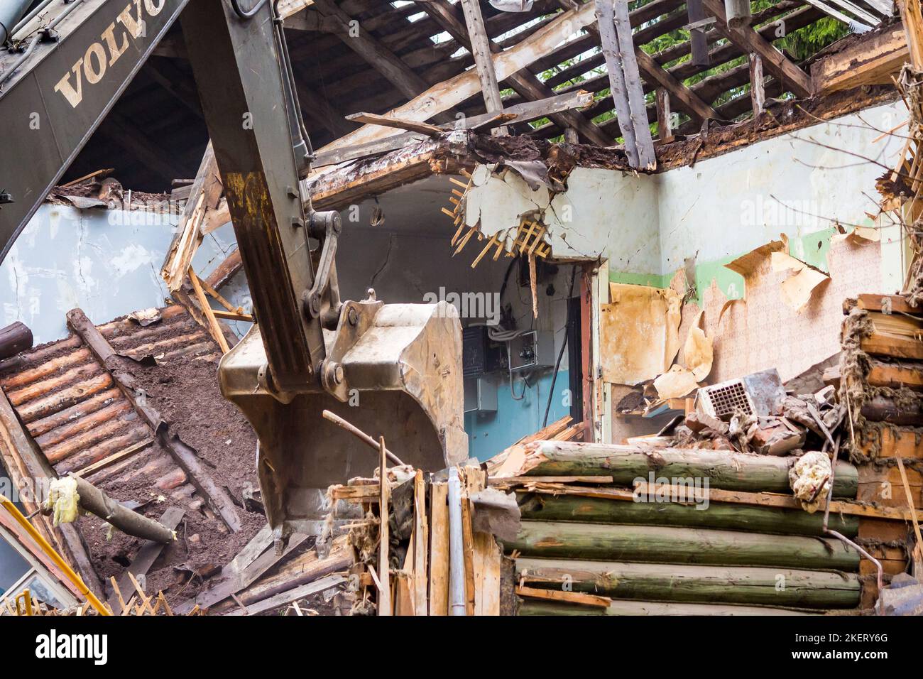 Demolition of an old wooden log house with a Volvo excavator, the ...
