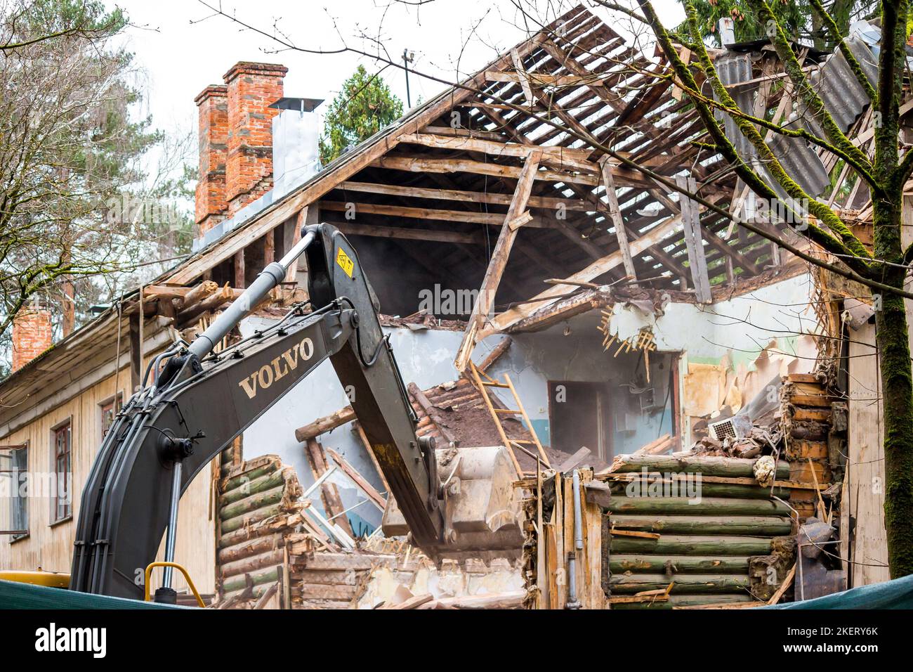 Demolition of an old wooden log house with a Volvo excavator, the ...