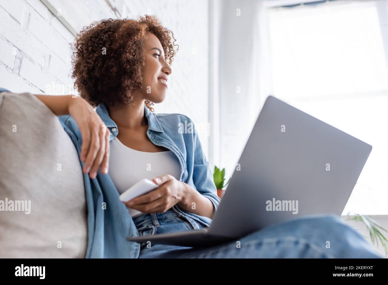 low angle view of happy african american woman holding smartphone near ...