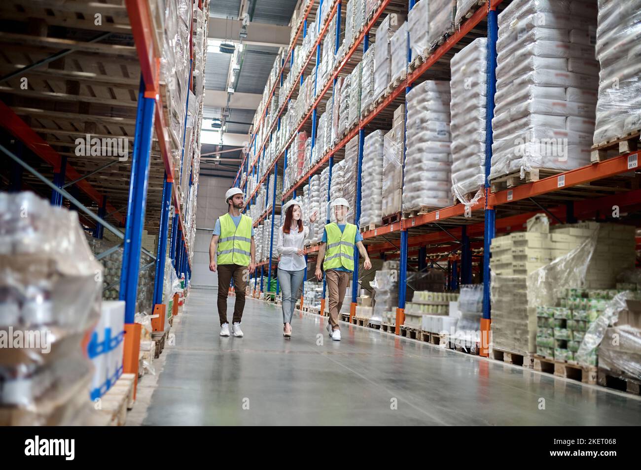 Serious female supervisor and warehouse employees inspecting a racking ...