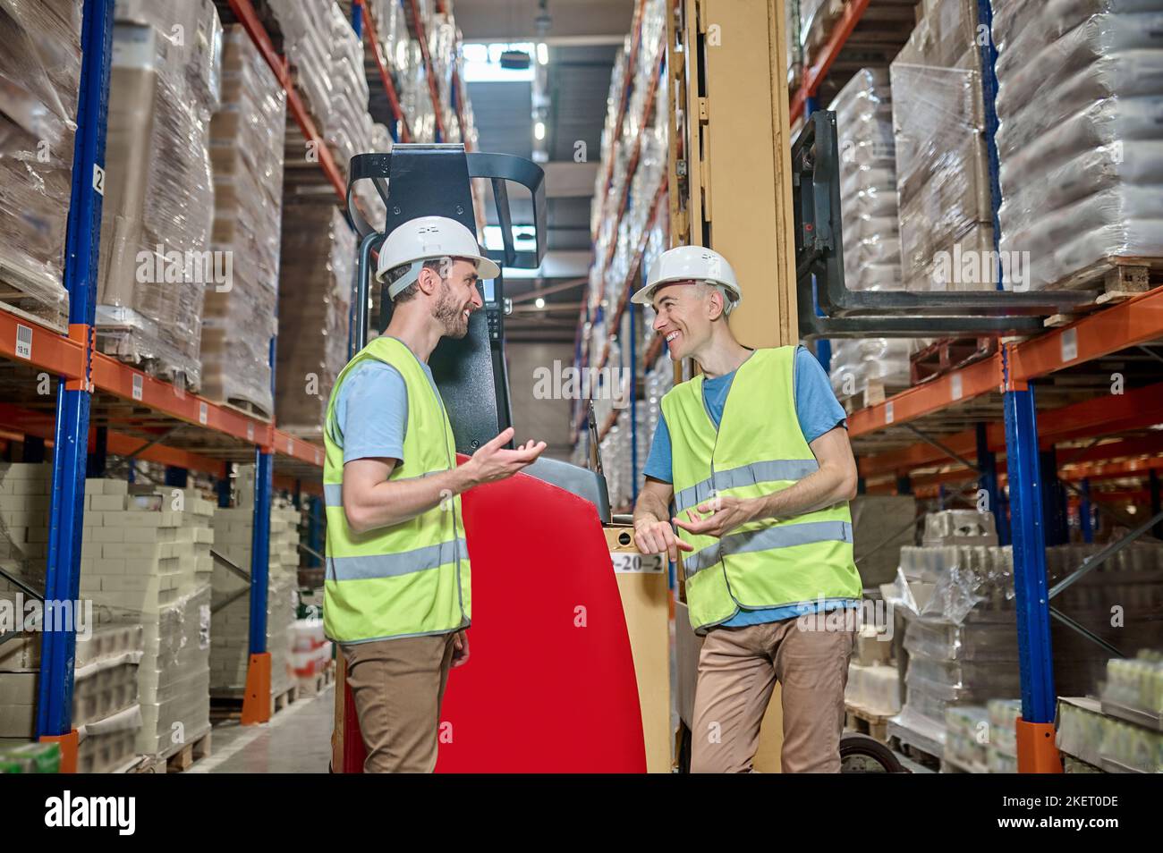 Joyous warehouse staff standing among the pallet racks with goods Stock ...