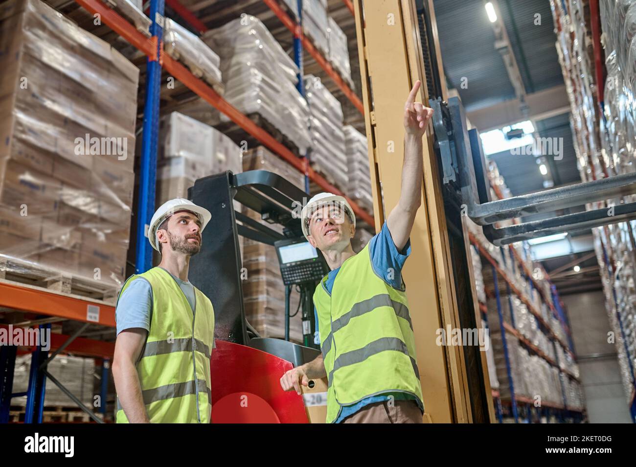 Warehouse personnel in protective helmets inspecting a racking system ...
