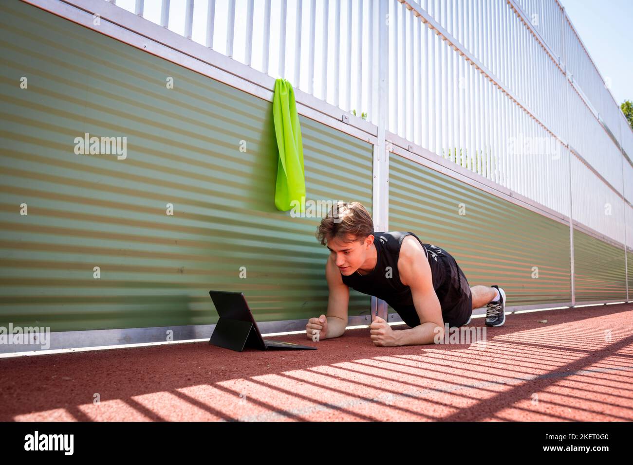 Fitness good looking healthy man doing planks watching online tutorials ...