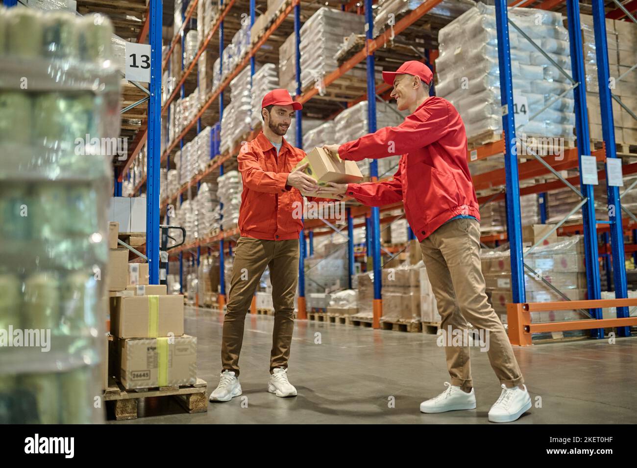 Two loaders unloading boxed goods in the warehouse facility Stock Photo ...