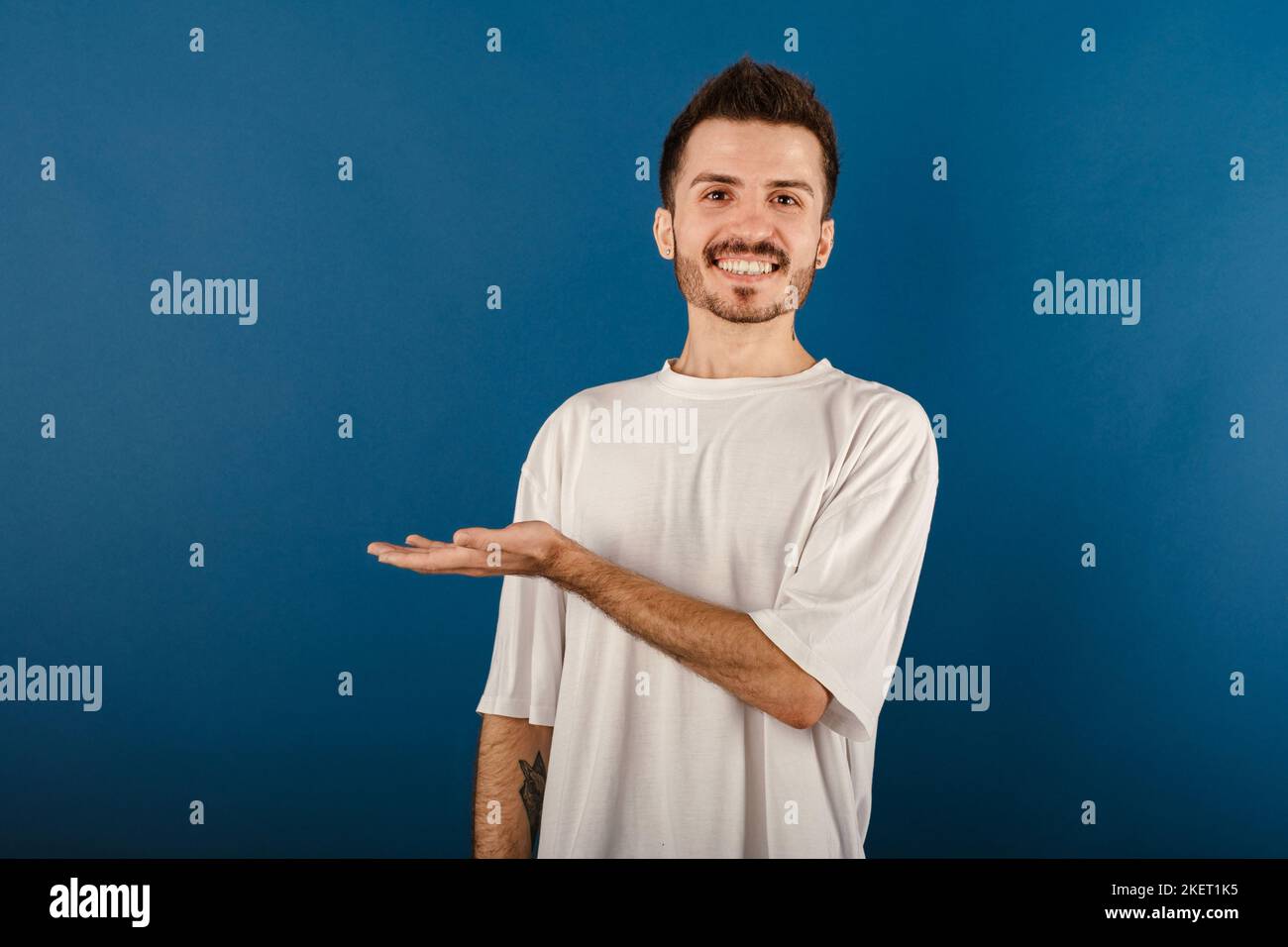 Happy casual man wearing t-shirt posing isolated over blue background ...