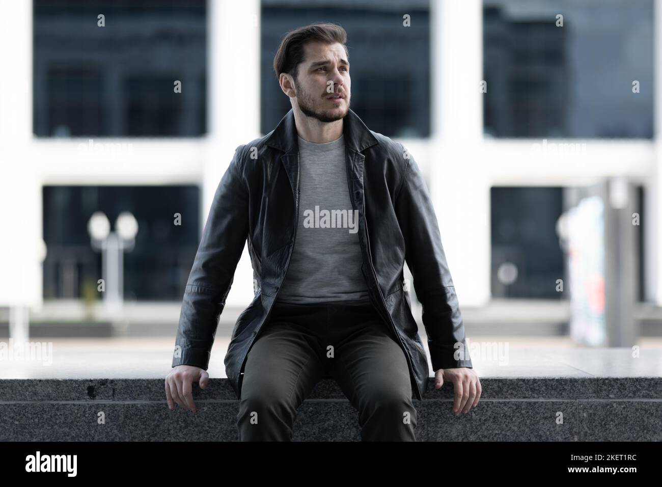 confused man in depression sitting on the parapet unemotional looking ...