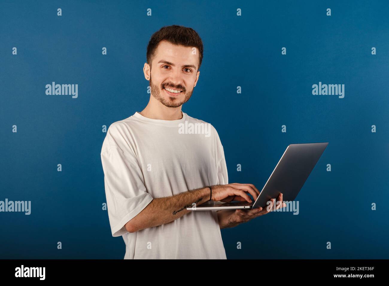 Happy young man wearing white t-shirt posing isolated over blue ...